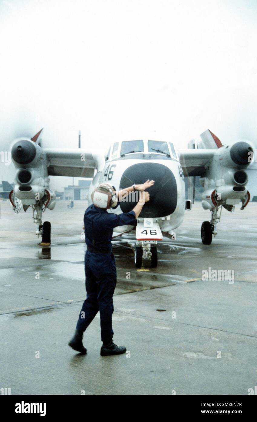 A ground crew member signals the pilot of a Fleet Logistics Support ...