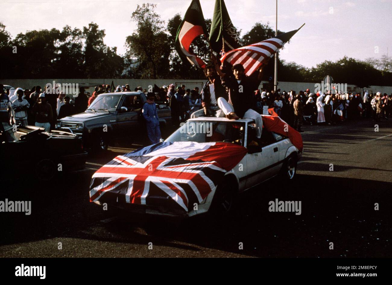 Flags of nations in the Coalition are displayed on a car in a parade ...