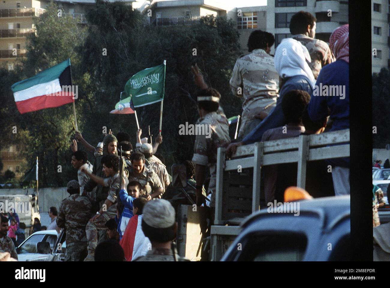 Soldiers wave flags in a parade celebrating the liberation of Kuwait ...