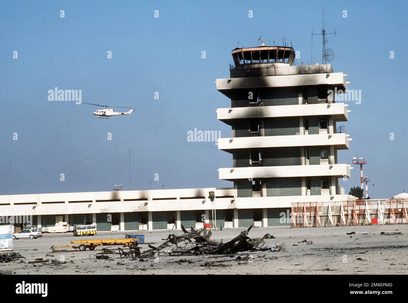 A UH-1N Iroquois helicopter flies by the battle-damaged control tower ...