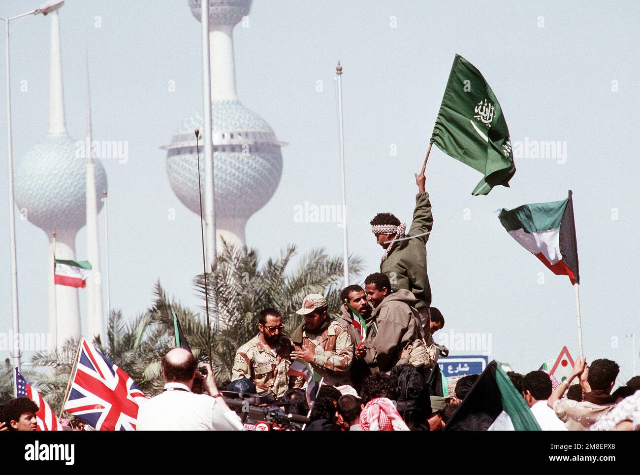 American, British, Saudi and Kuwaiti flags are held aloft by ...