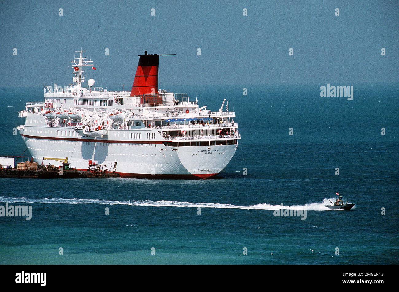 A patrol craft speeds past the cruise ship RMS Cunard Princess ...