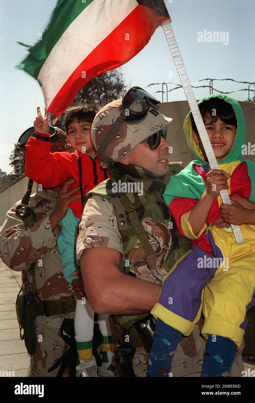 A U.S. Army captain holds up a girl waving a Kuwaiti flag as civilians ...