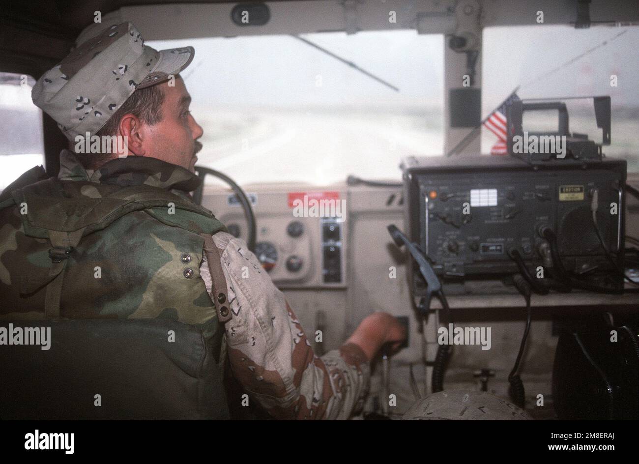 A soldier monitors a radio as he drives an M998 High-Mobility ...