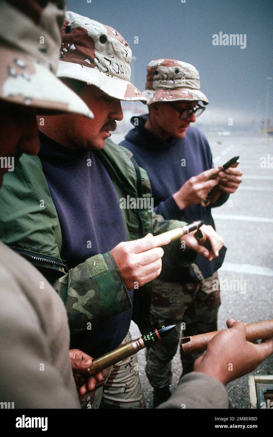 Members of an explosive ordnance disposal (EOD) unit examine round of ...
