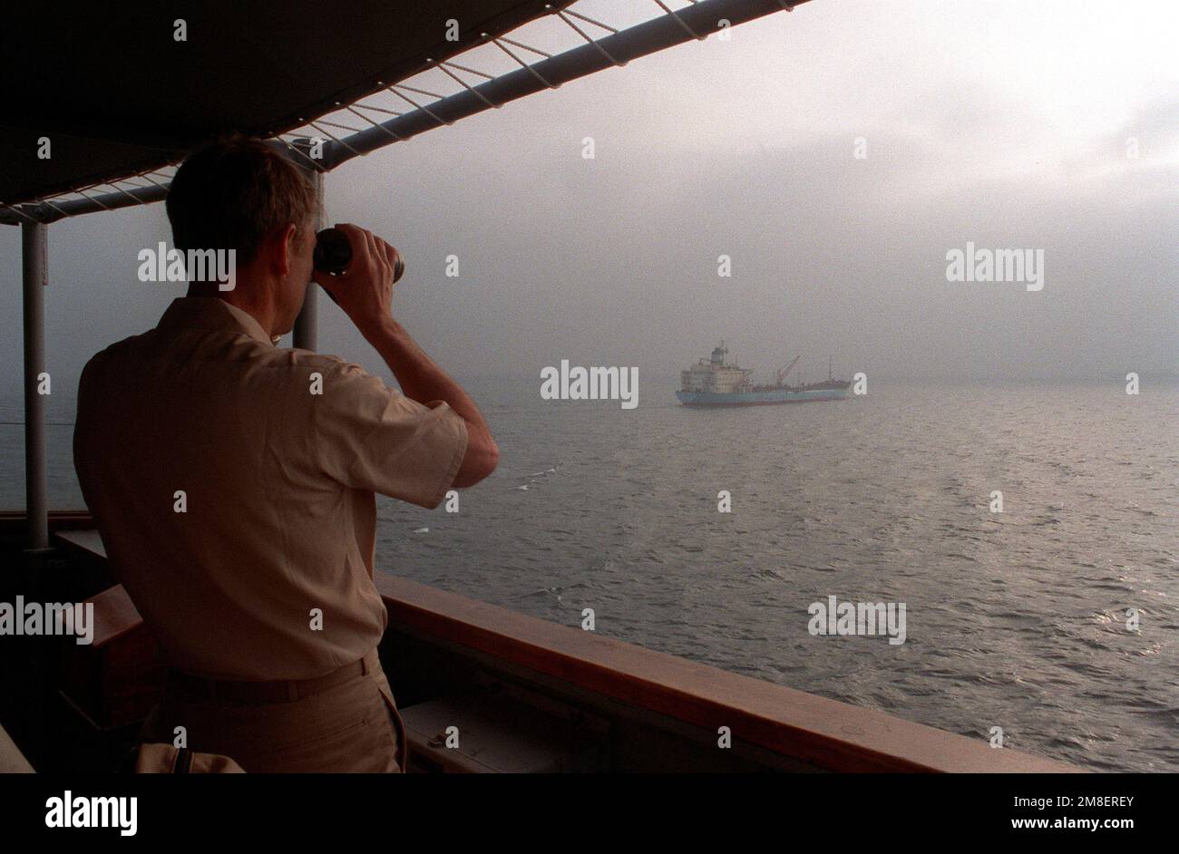 CAPT. Douglas C. Bauer, a U.S. Navy historian, watches a passing ship ...