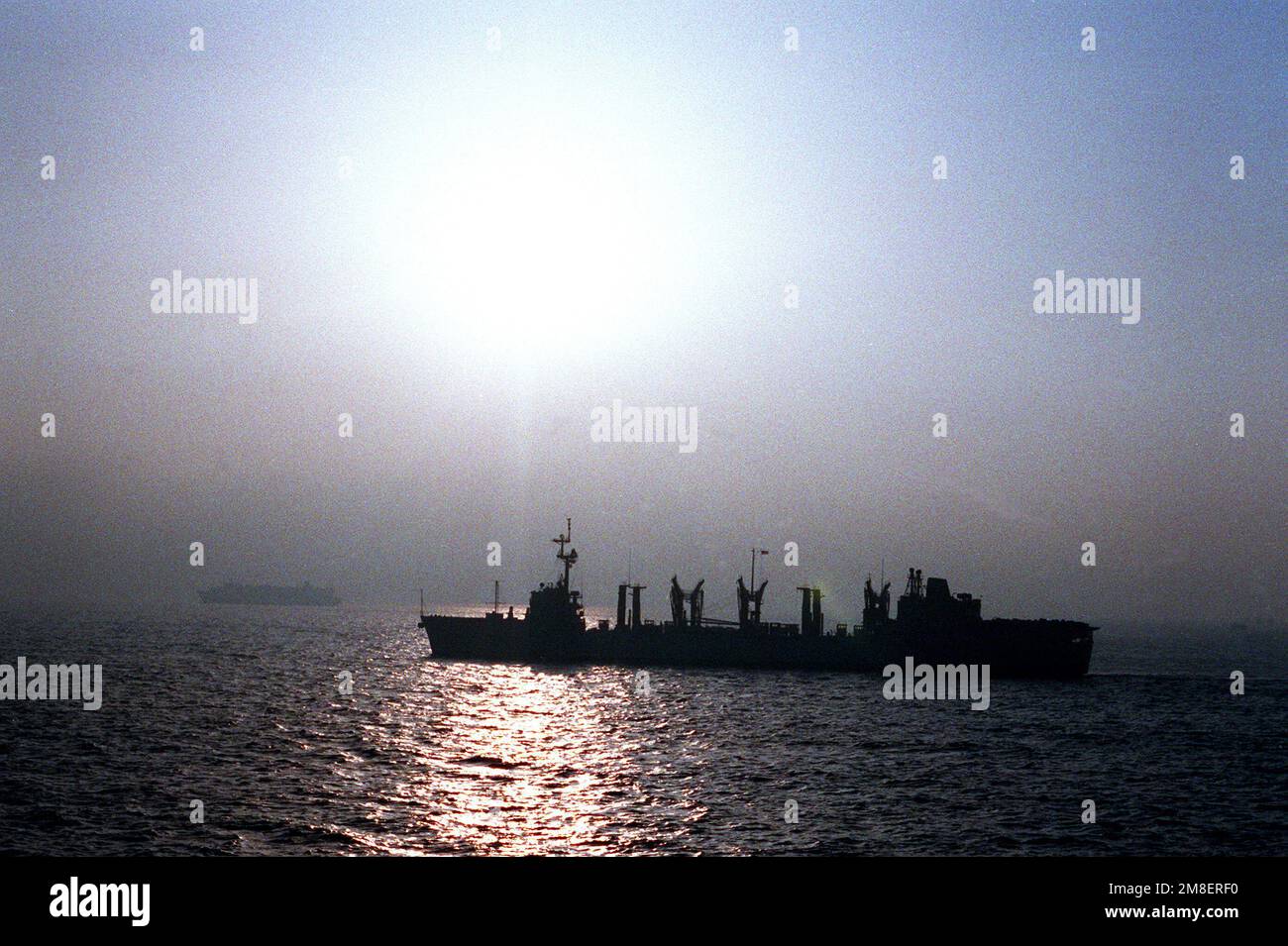 A Wichita class replenishment oiler is silhouetted in the late ...