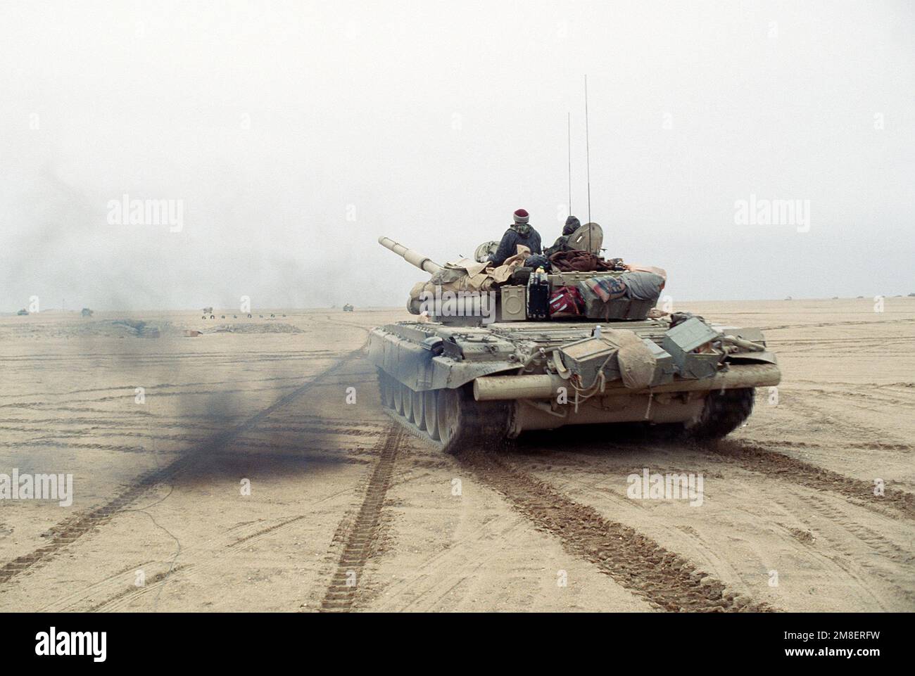 Members of the Coalition forces drive a T-72 main battle tank along a ...