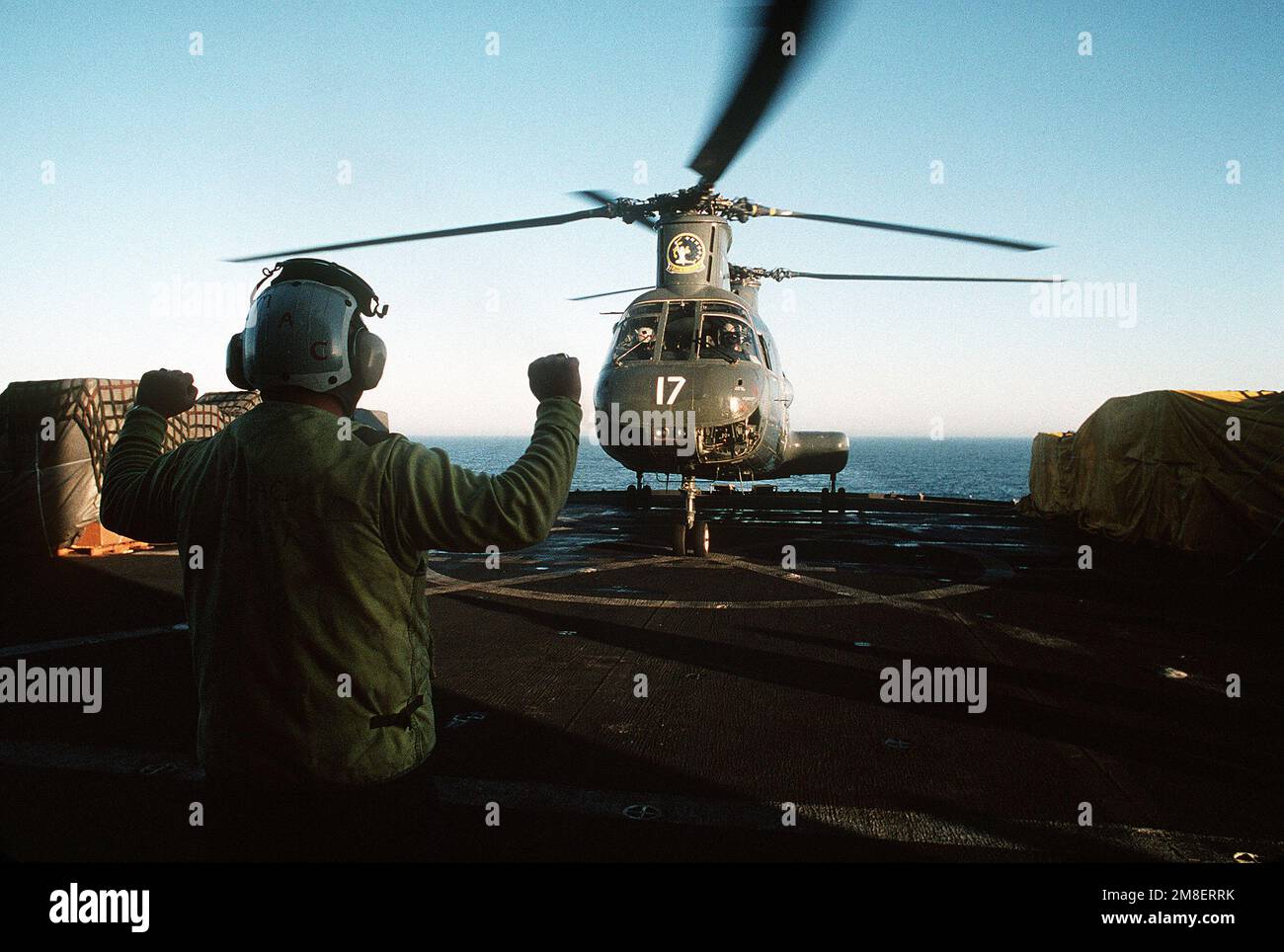 A flight deck crew member guides the pilot of a Helicopter Combat ...