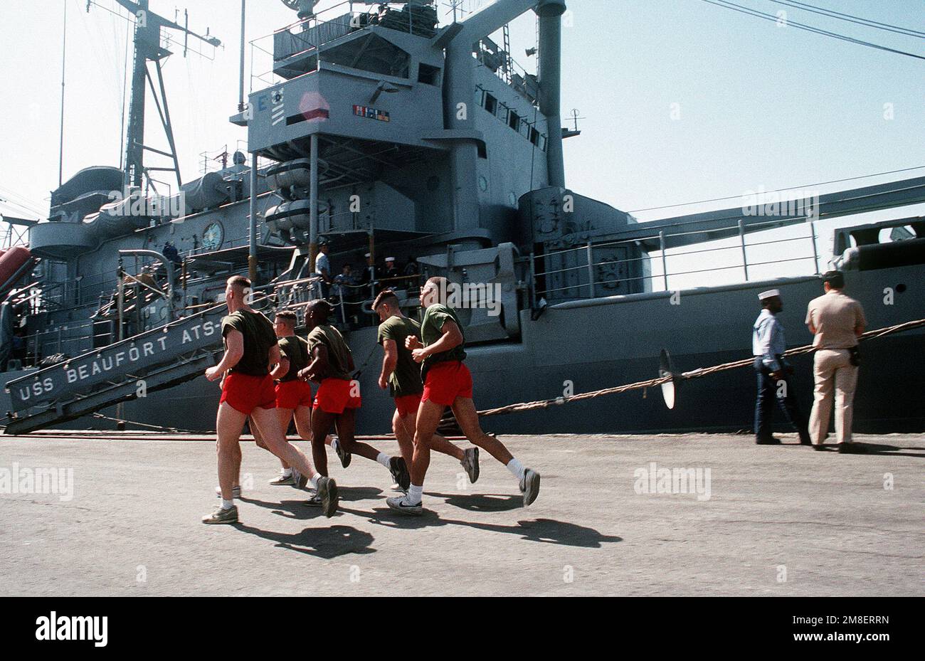 Marines run along Mina Salman pier past the salvage and rescue ship USS ...