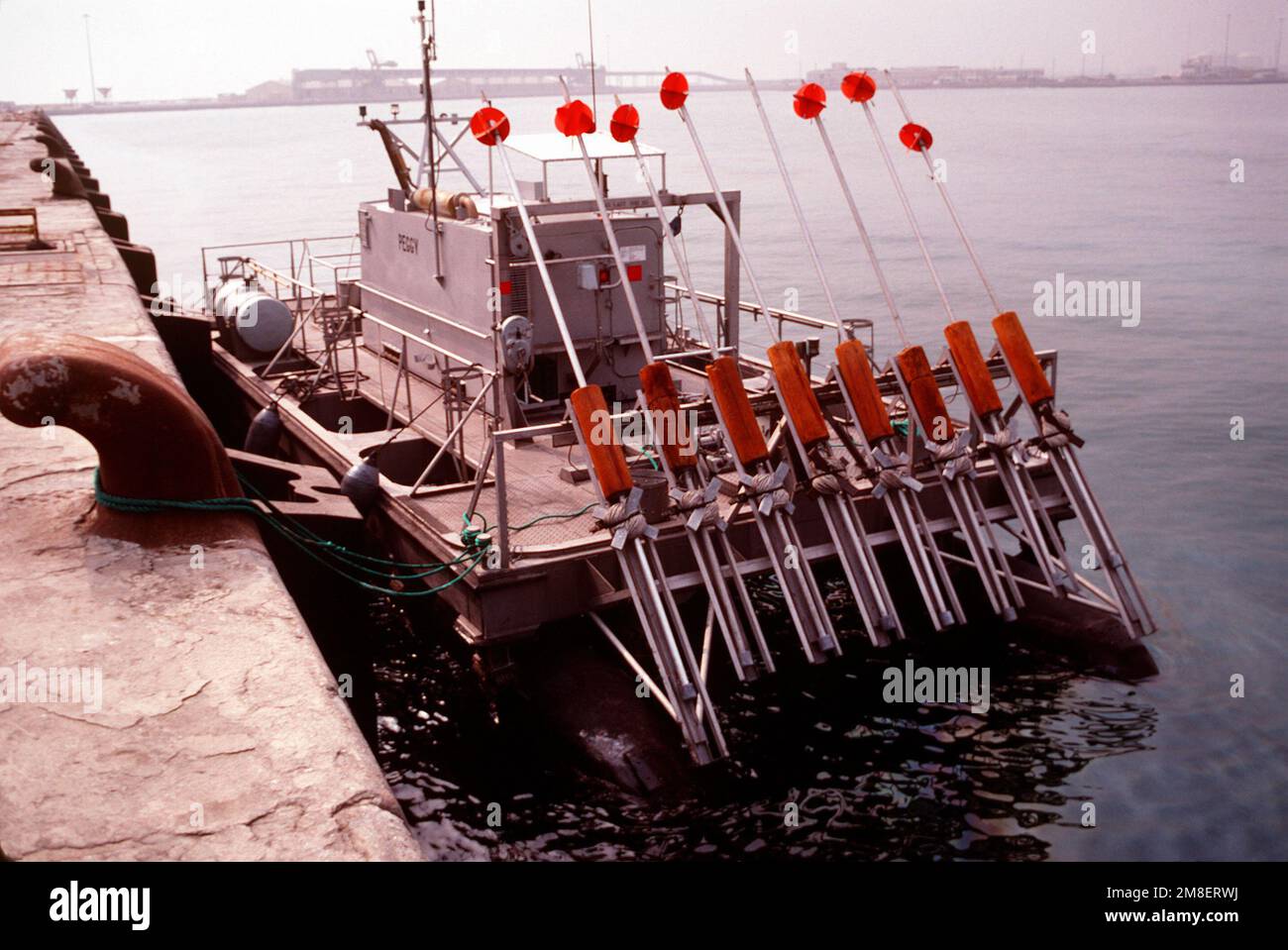 A mine marking barge is moored to the pier prior to being used by ...