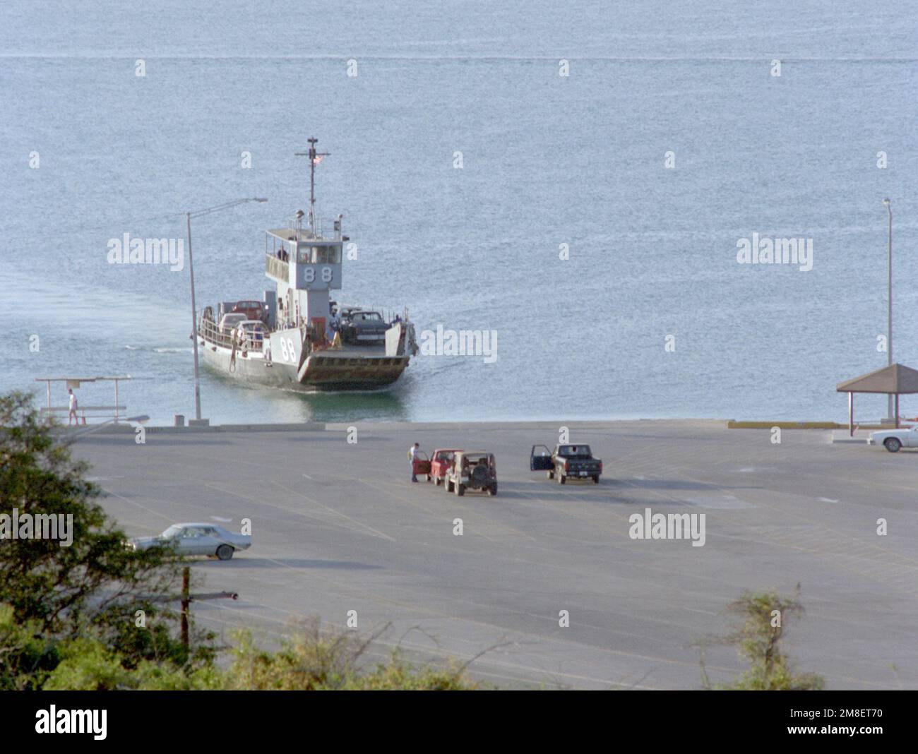 Three vehicles wait on shore as the ferryboat YFB-88 approaches the ...