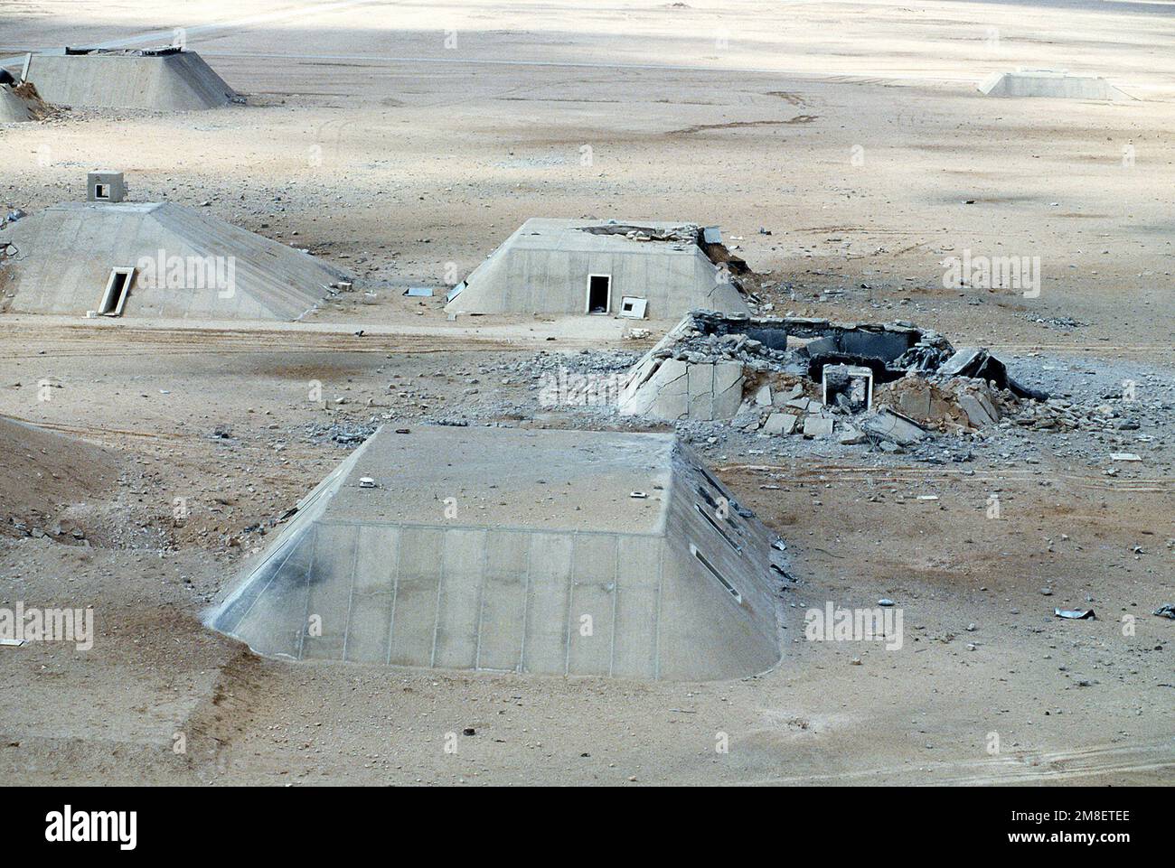 A view of a demolished munitions bunker and others showing some damage ...