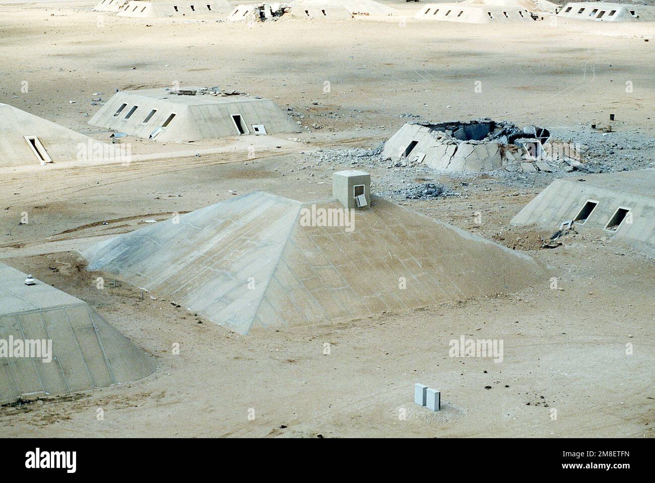 A view of a demolished munitions bunker and others showing some damage ...
