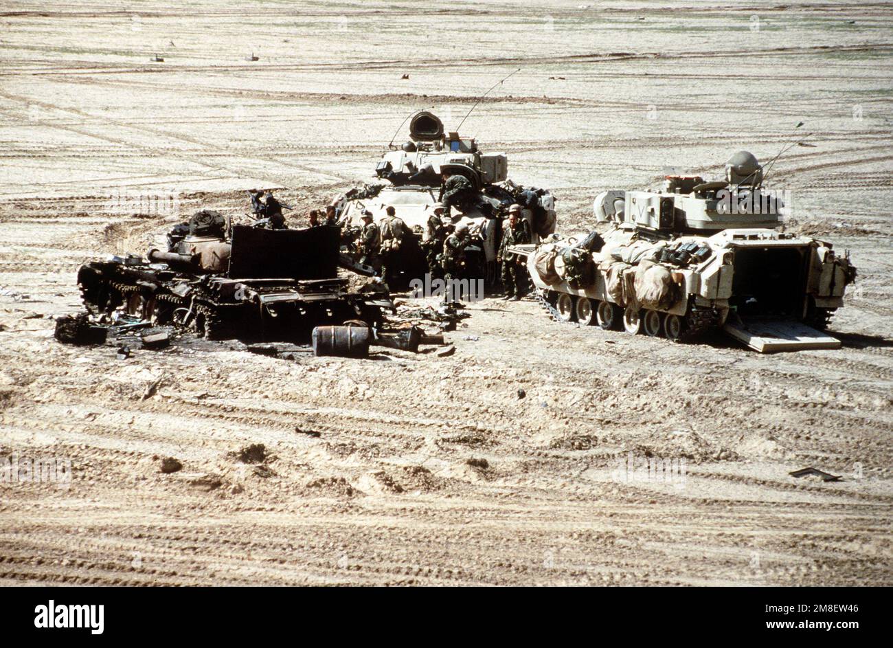 U. S. military personnel gather near a demolished Iraqi T-72 main ...