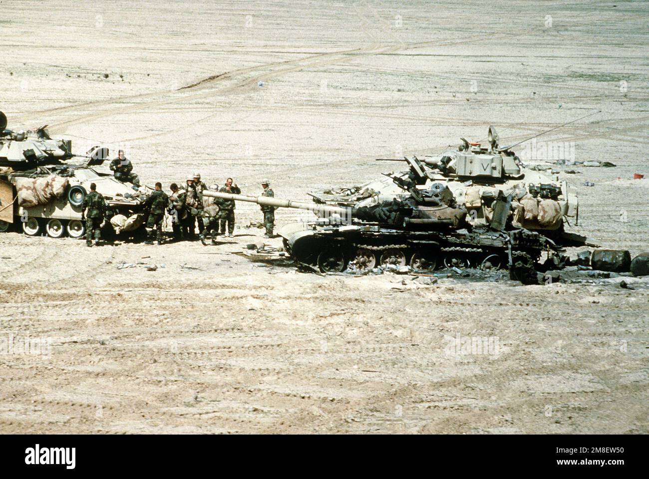 U.S. military personnel gather near a demolished Iraqi T-72 main battle ...