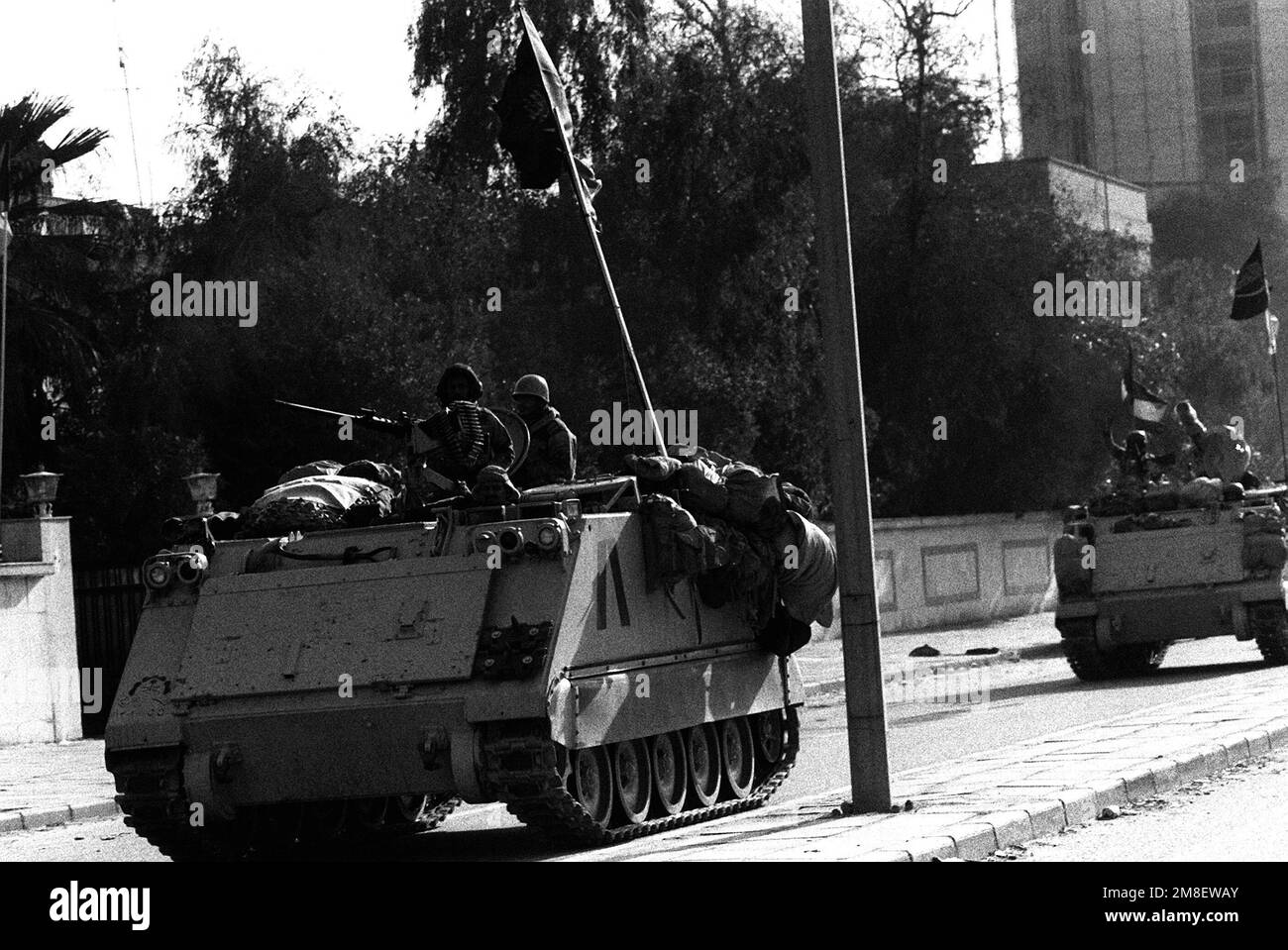 Members of a coalition armoured unit move down the street in M-113 ...