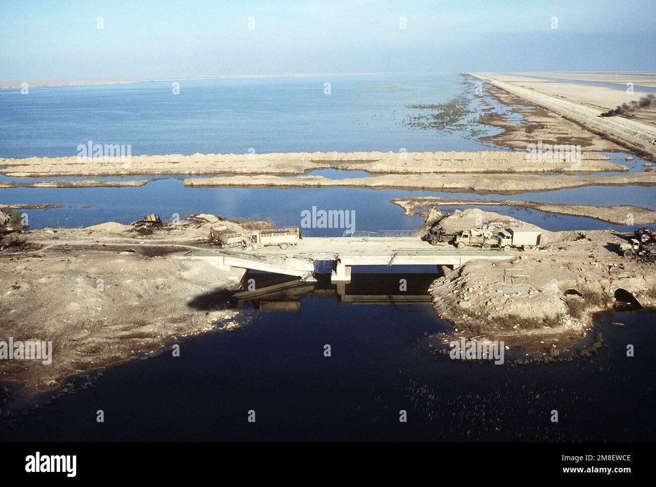 A view of a partially collapsed bridge and abandoned Iraqi trucks on a ...