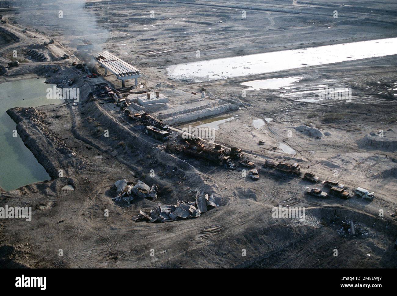 Demolished Iraqi vehicles line a roadway near a section of elevated ...