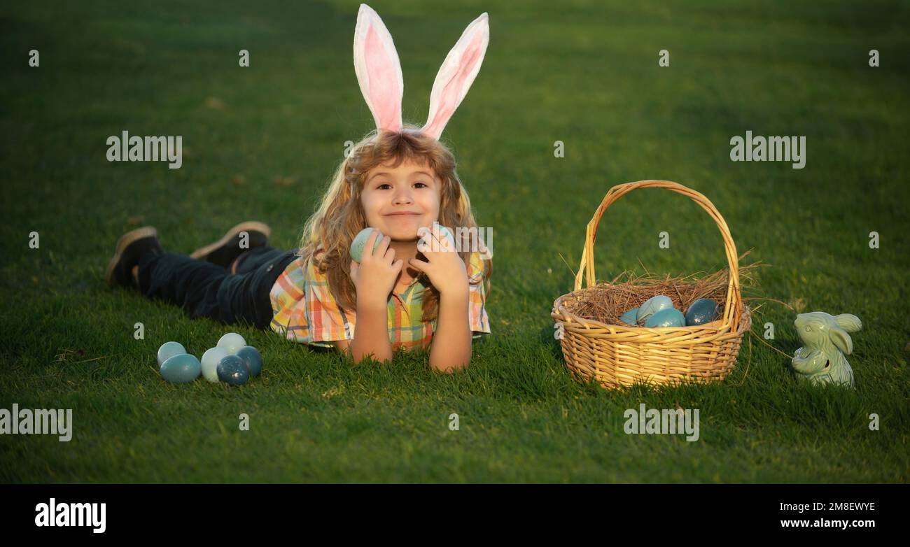 Child boy hunting easter eggs in spring lawn laying on grass. Bunny ...