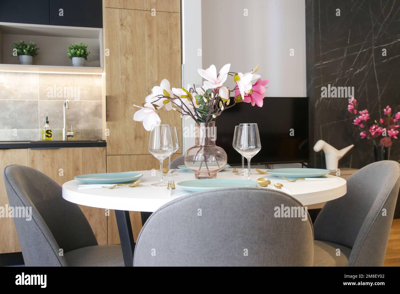 Round dining table in modern apartment, table setting with flowers for ...
