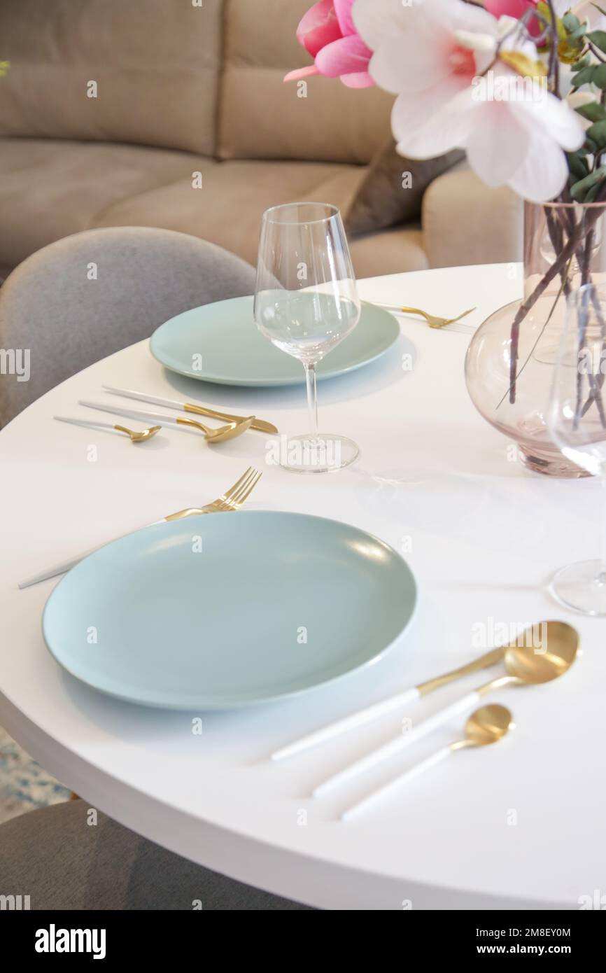 Round dining table in modern apartment, table setting with flowers for ...