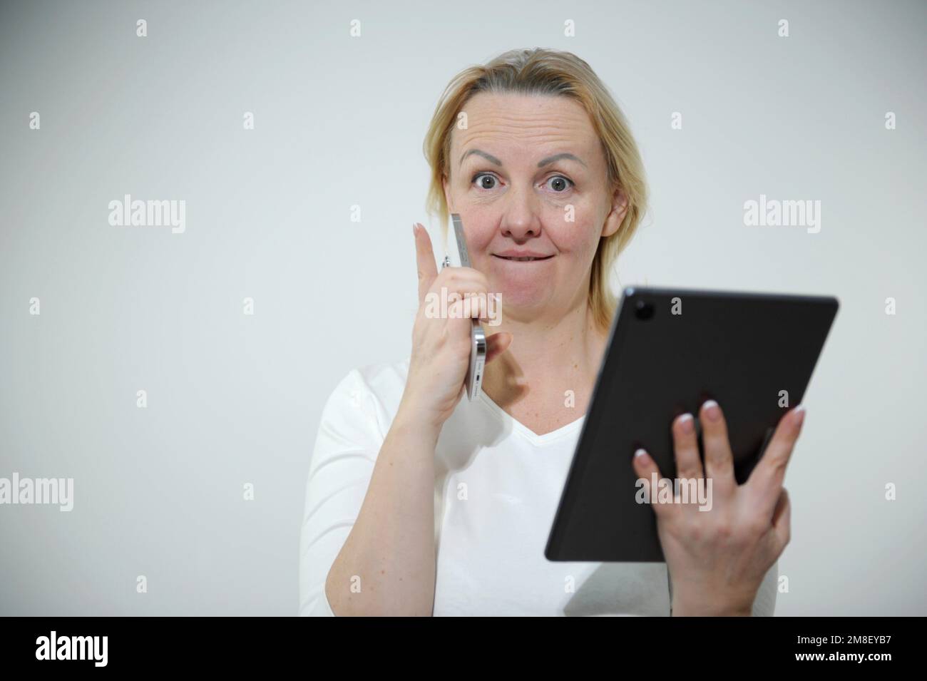 adult woman is talking on phone and holding tablet hand she raised ...