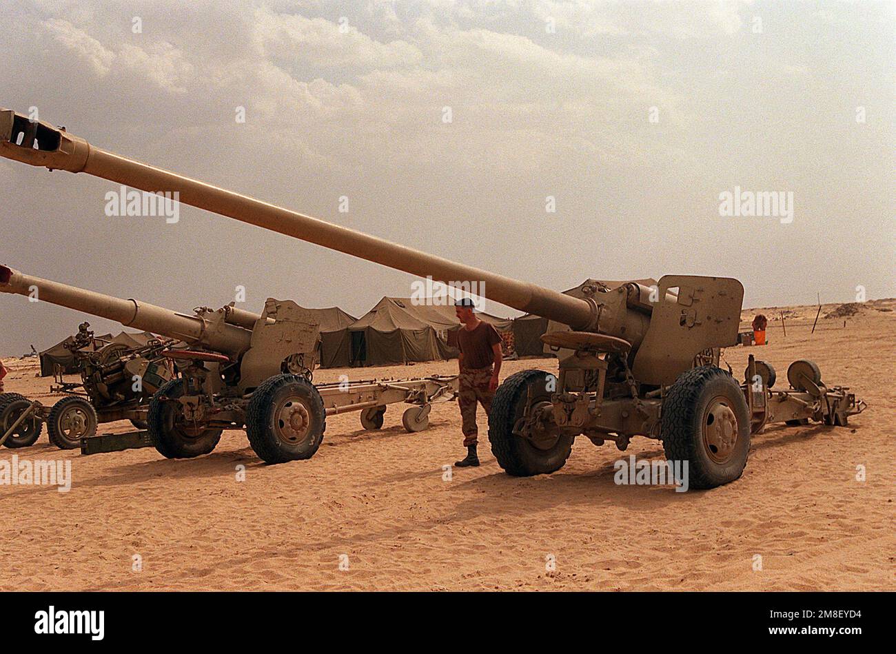 A Marine walks between a Type 59 130mm field gun, right, and a D-20 ...
