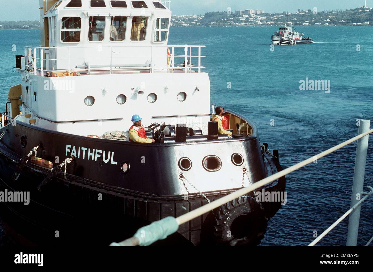 The Bermudan tug boat FAITHFUL pulls up to the bow of the guided ...