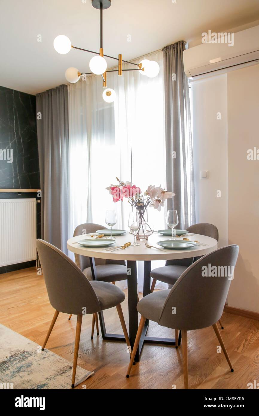 Round dining table in modern apartment, table setting with flowers for ...