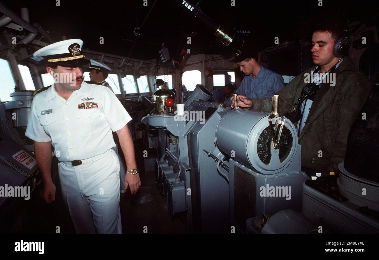 An officer speaks to the lee helmsman on the bridge of the guided ...