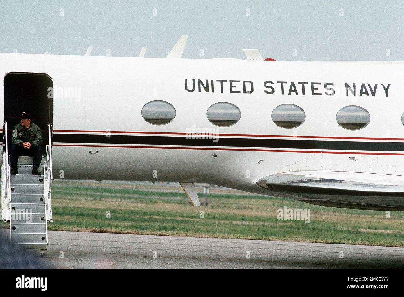 A flight crew member sits on the steps of a Fleet Logistics Support ...