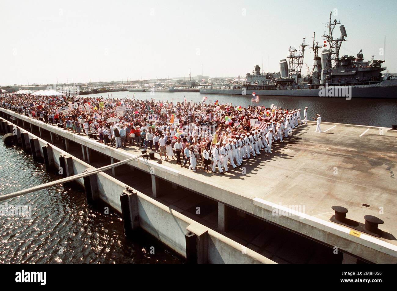A line of sailors holds back the crowd gathered to greet the guided ...