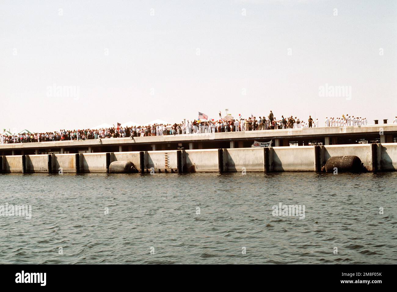 A line of sailors holds back the crowd gathered to greet the guided ...