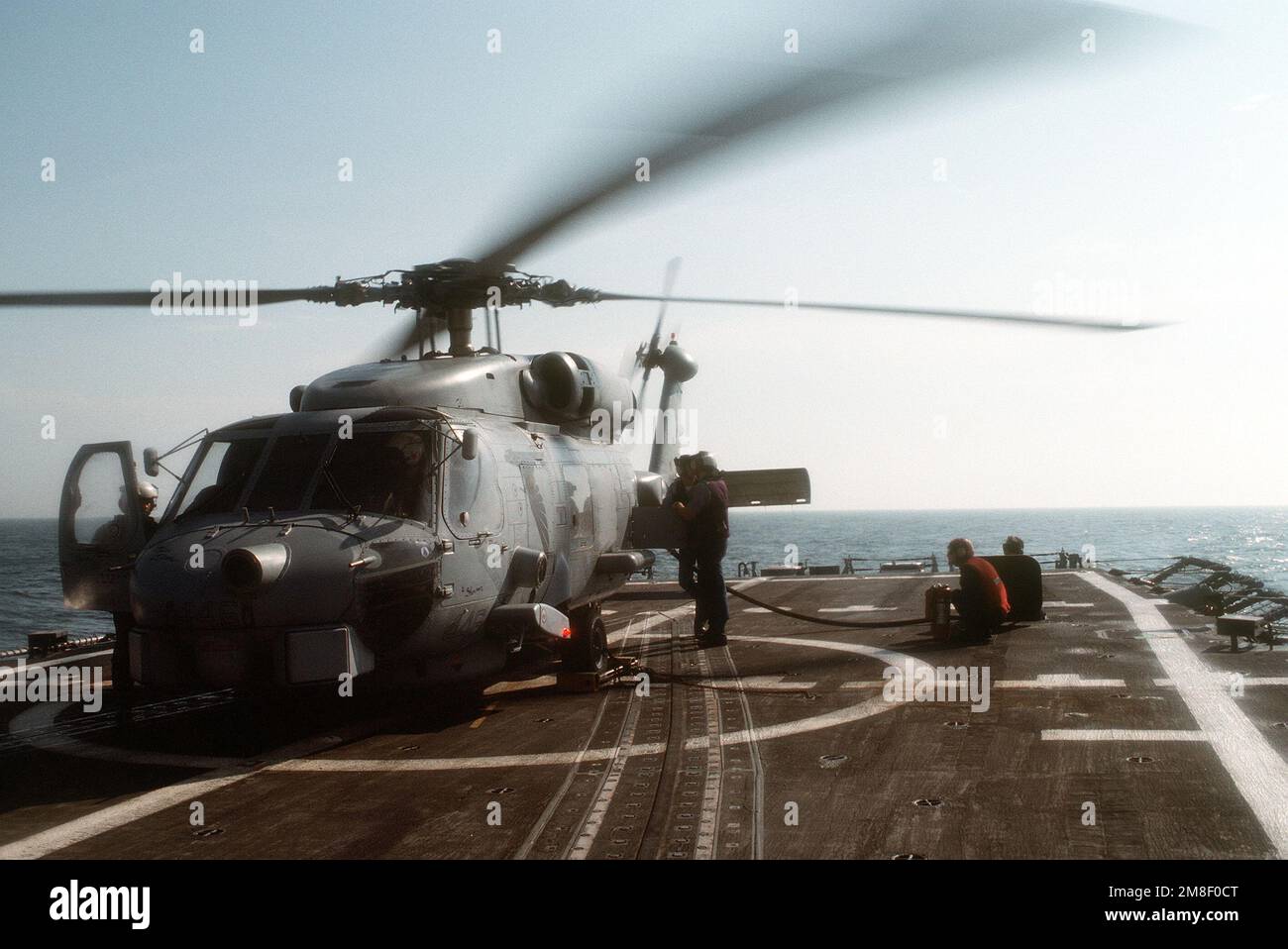 Flight deck crewmen refuel an SH-60B Sea Hawk helicopter aboard the ...