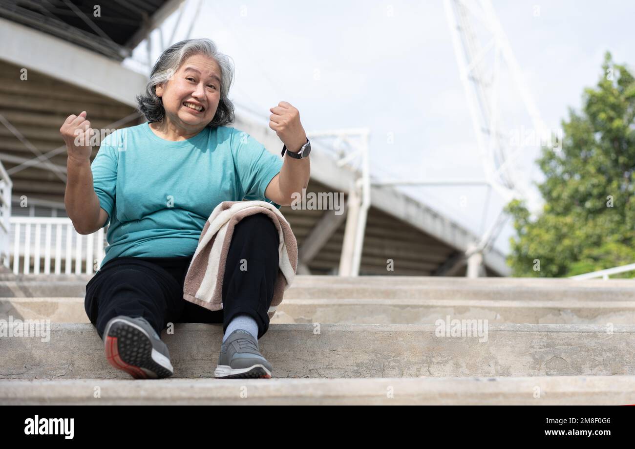Happy and smile elderly asian woman sitting on stairs for rest after ...
