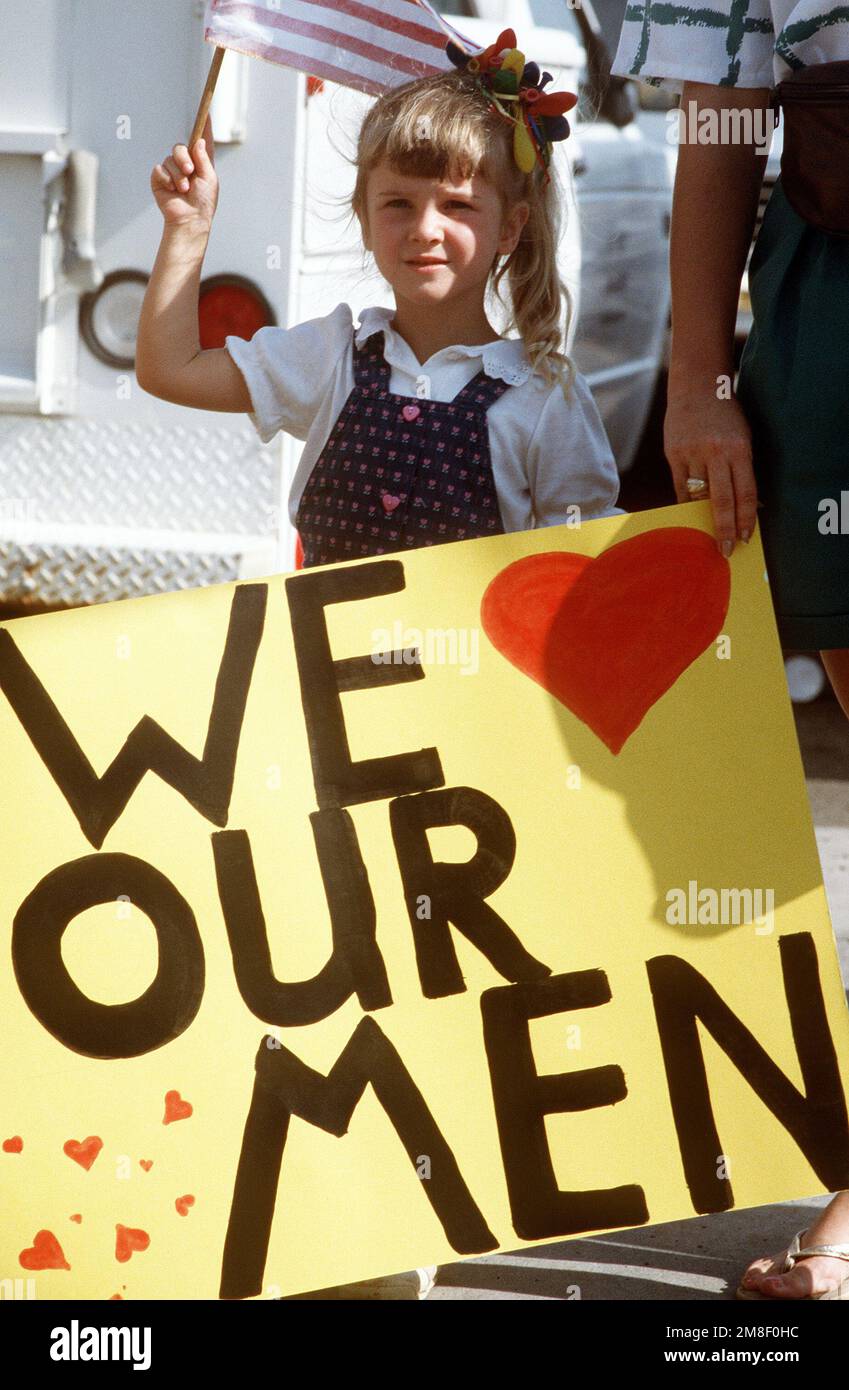 A child stands behind a sign held by her mother as they welcome the ...