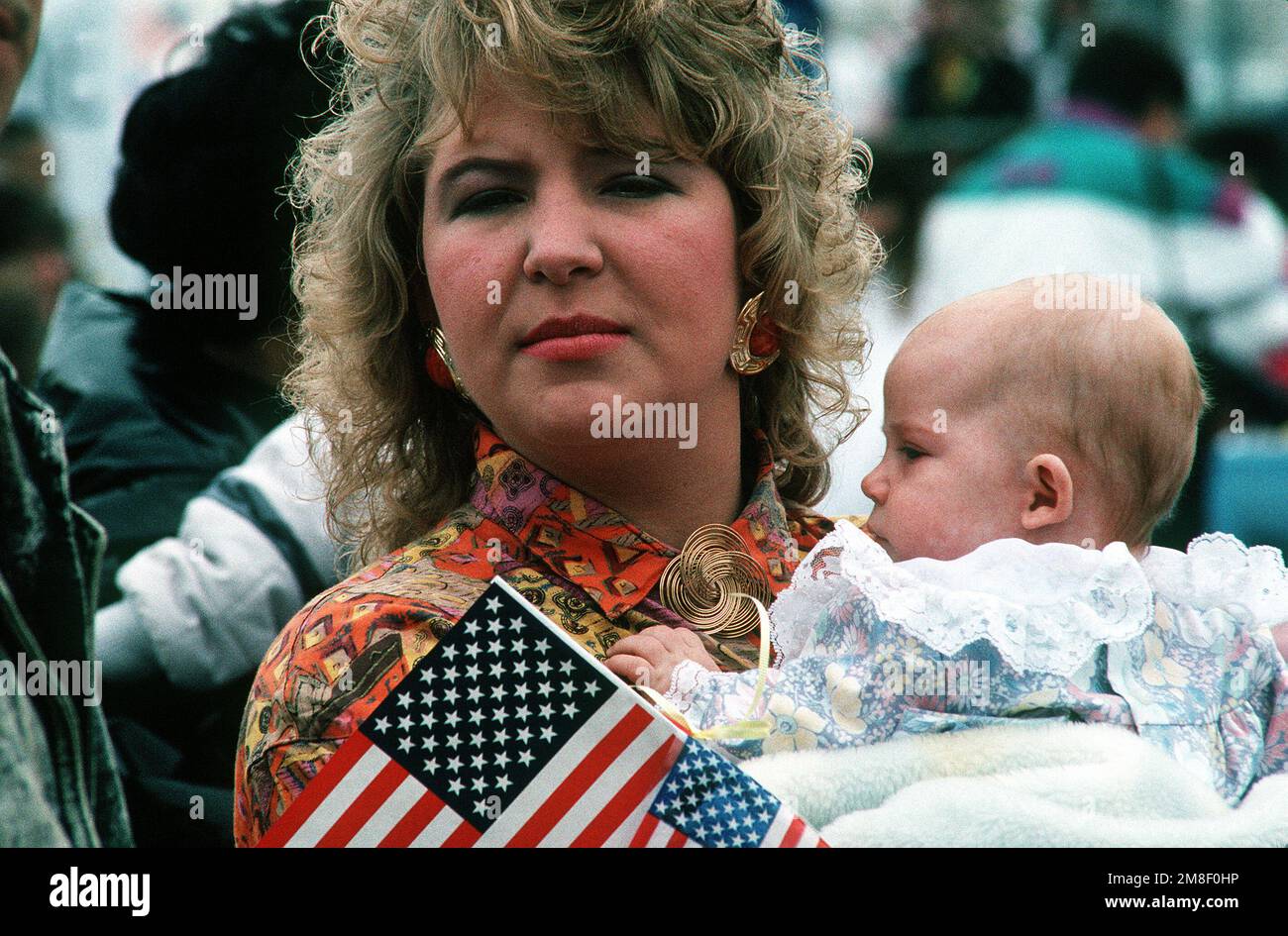 A mother holds her baby girl as she waits for the return of her husband ...