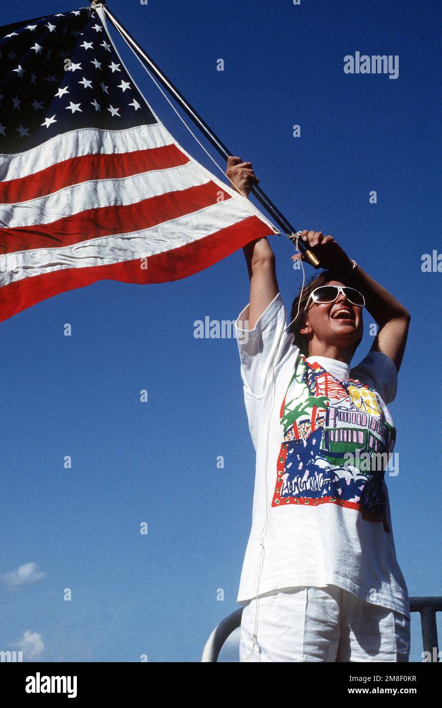 A woman waves a flag as she stands on the pier to welcome the ...