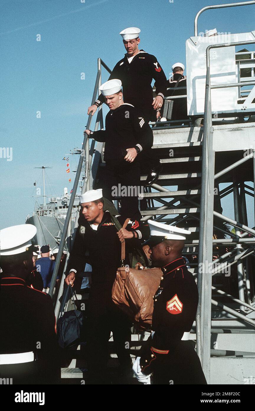 Sailors depart down the brow just minutes after their ship is tied up ...