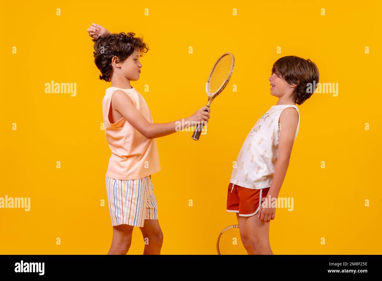 Two kids playing tennis and having fun, yellow background Stock Photo ...