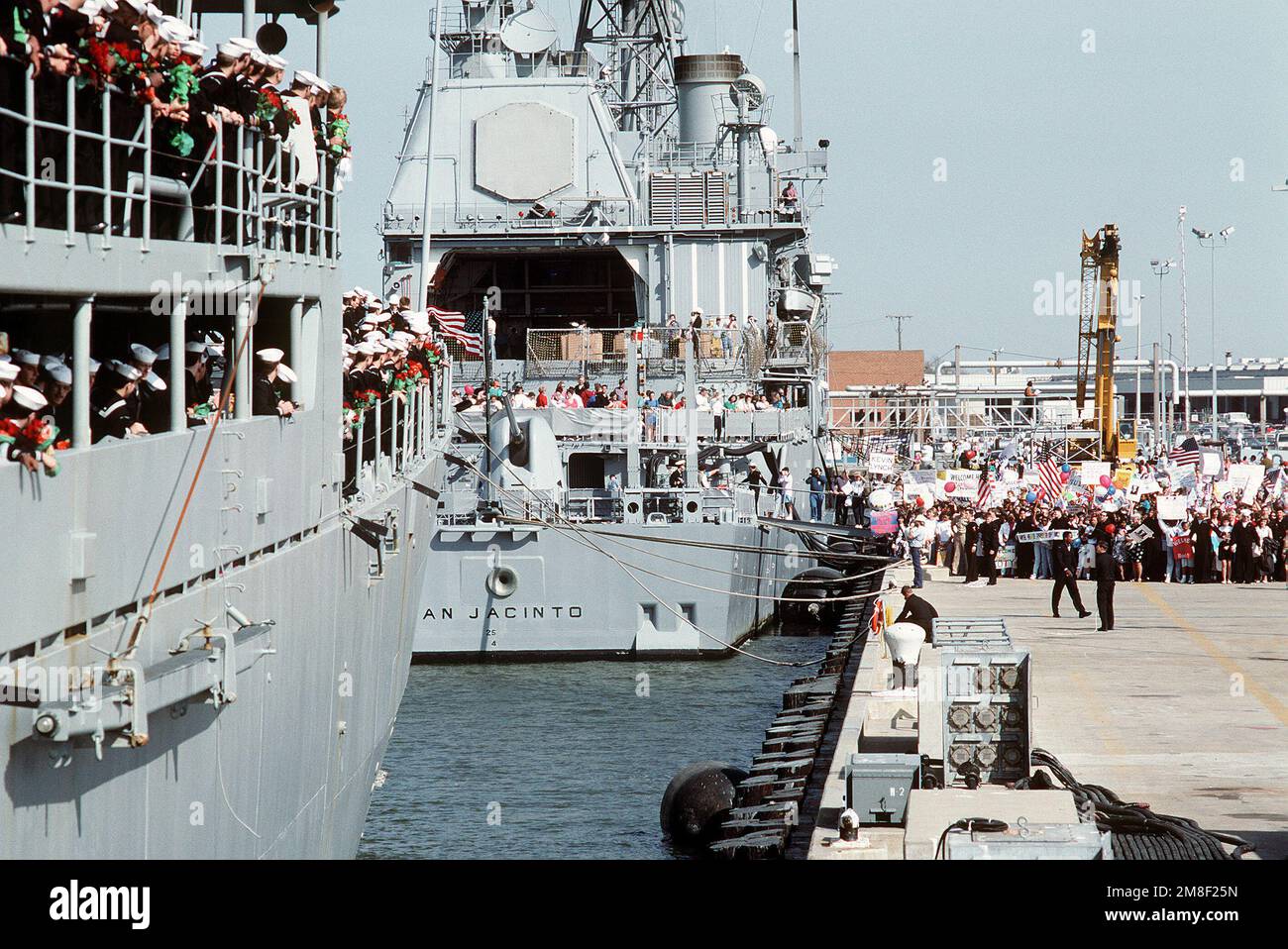 Crew members watch from the railing of the nuclear-powered guided ...