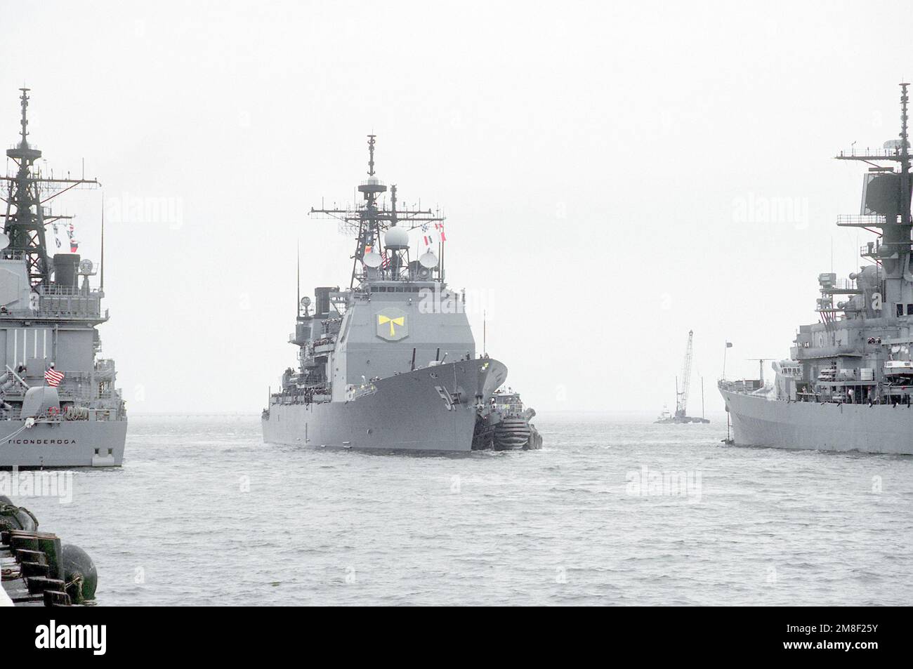 A large harbor tug comes alongside the guided missile cruiser USS ...