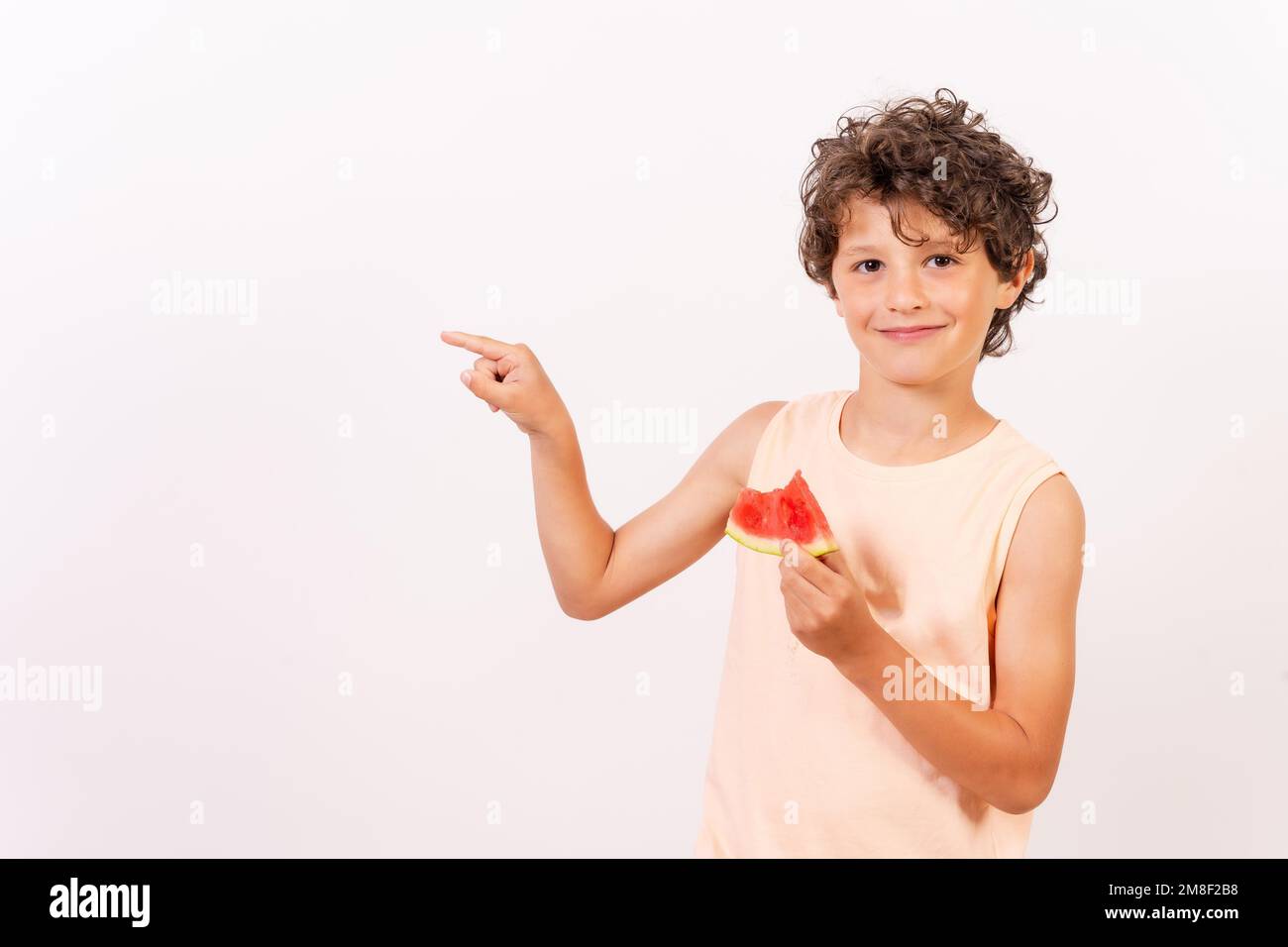 Boy eating a watermelon and pointing to the left, summer vacation ...