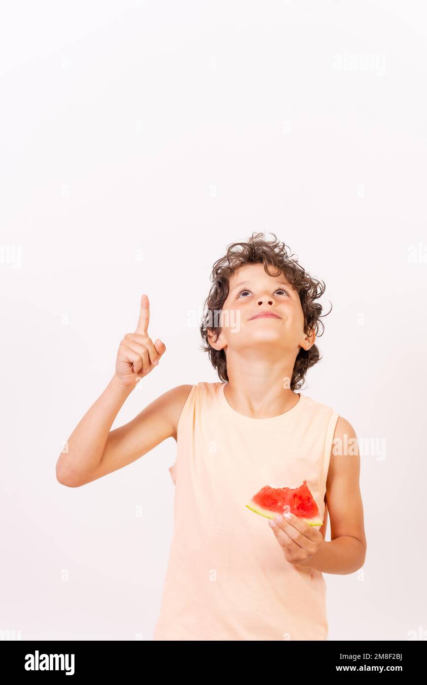 Boy eating a watermelon and pointing up, summer vacation. White ...