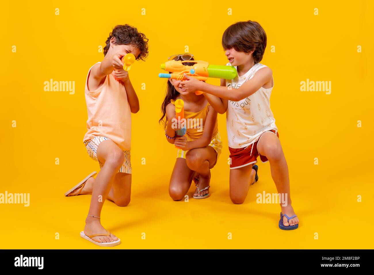 Kids having fun with water pistols on summer vacations and aiming at ...