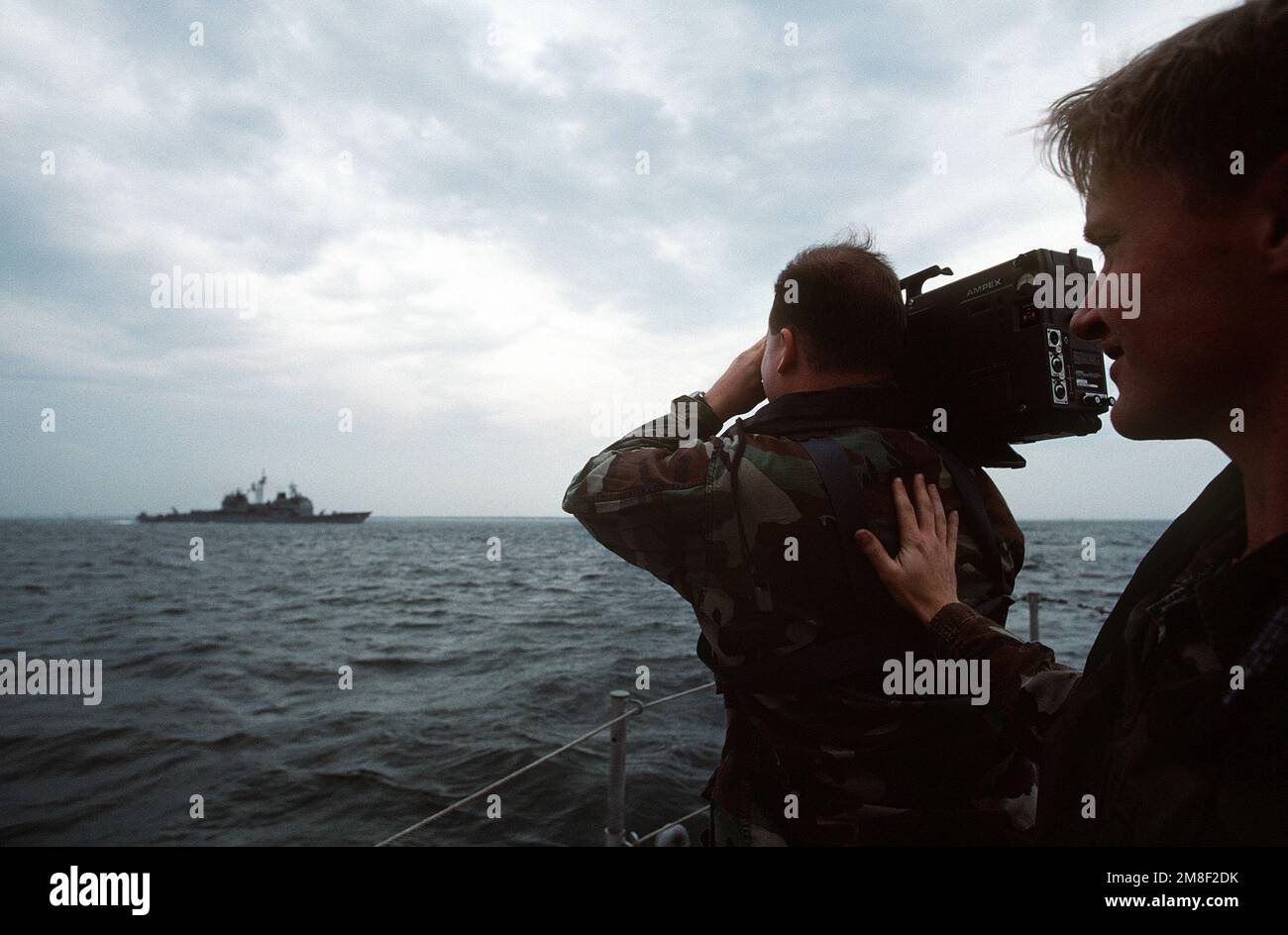 A video cameraman films the guided missile cruiser USS THOMAS S. GATES ...