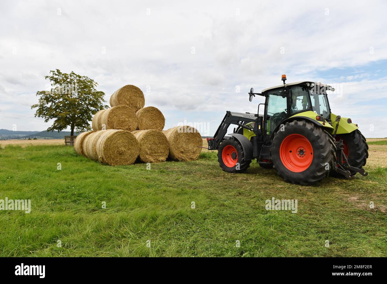 Tractor with bale fork stacking round bales, Hesse, Germany Stock Photo ...