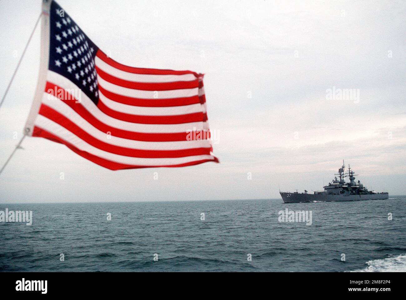 An American flag flies from the stern of another vessel as the nuclear ...