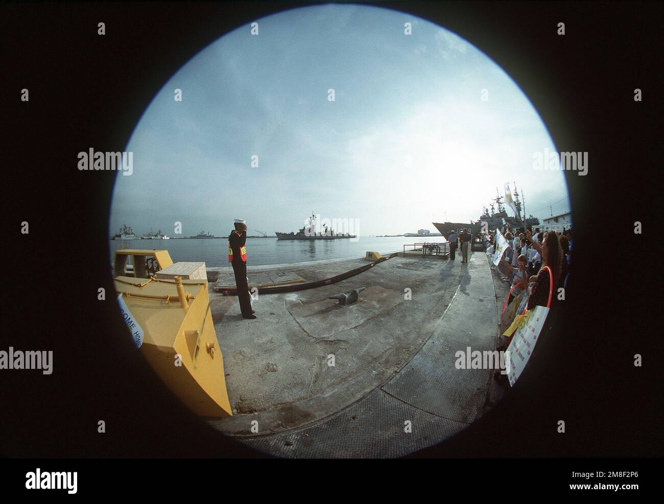 Viewed from a fish eye camera lens, a sailor stands by as a crowd ...